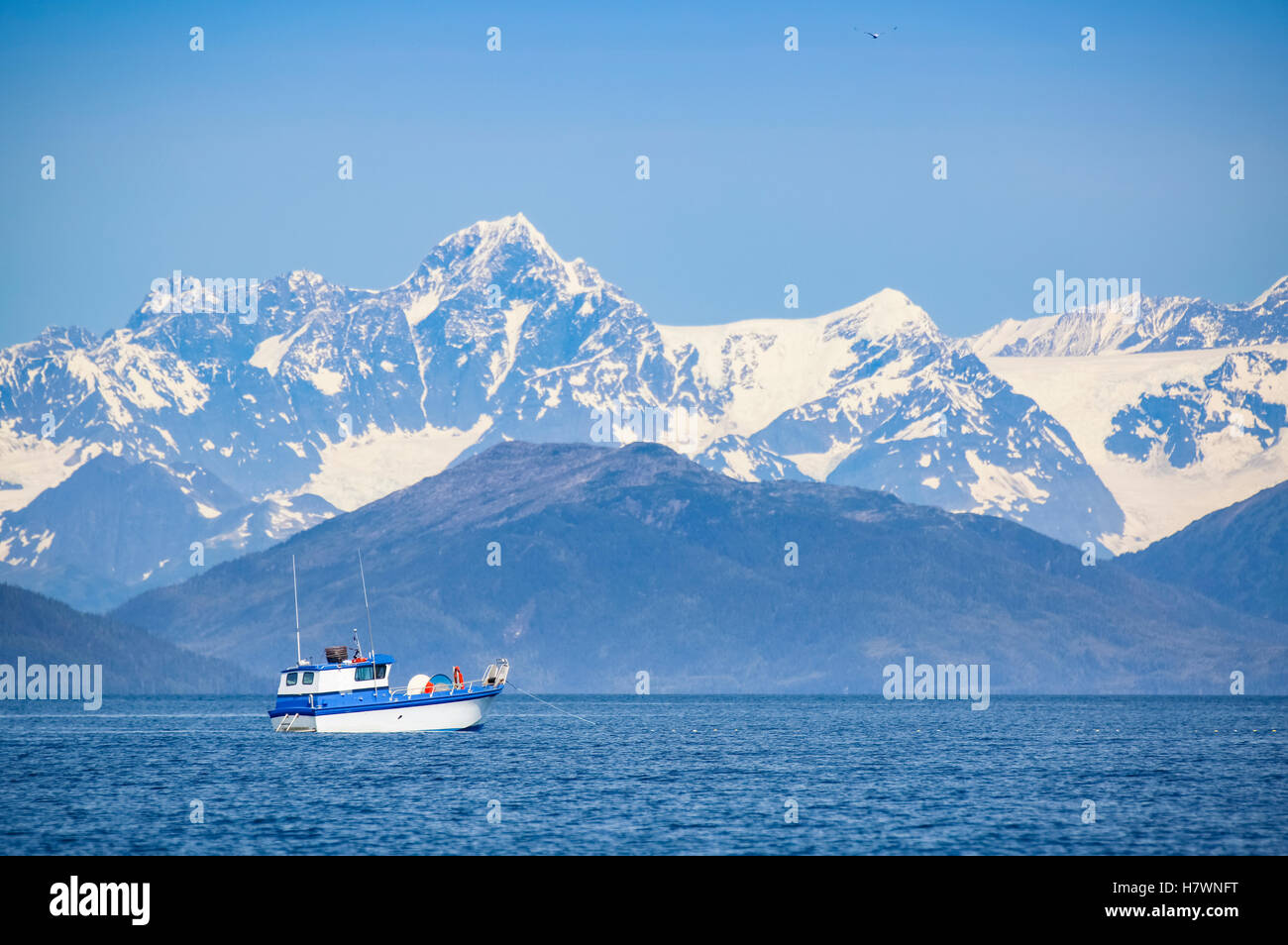 A small fishing boat on the waters of Main Bay, with the Chugach ...