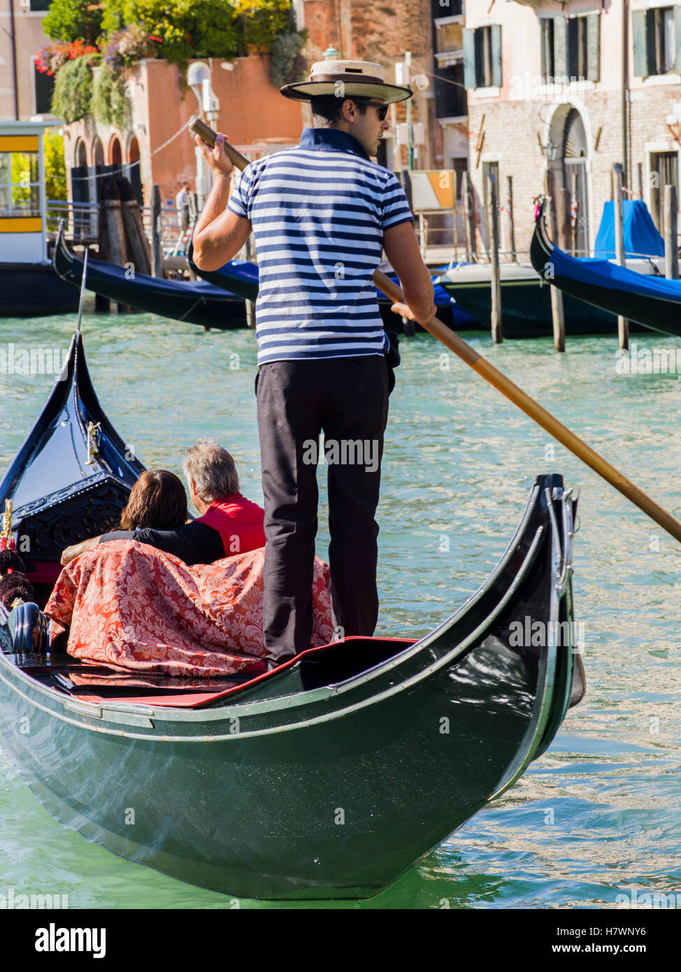 Gondola in a canal with gondolier in a striped shirt; Venice, Italy ...