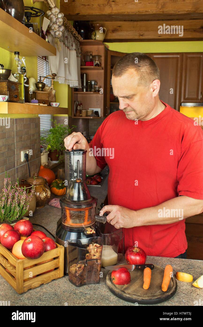 Man doing in the kitchen apple juice with carrot. Production of fruit ...
