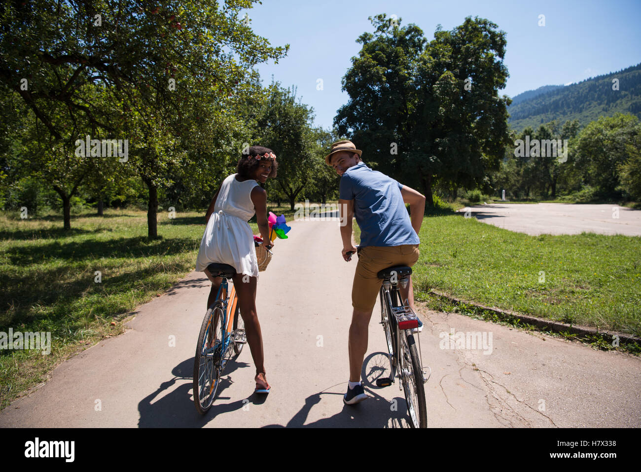 a young man and a beautiful black girl enjoying a bike ride in nature ...