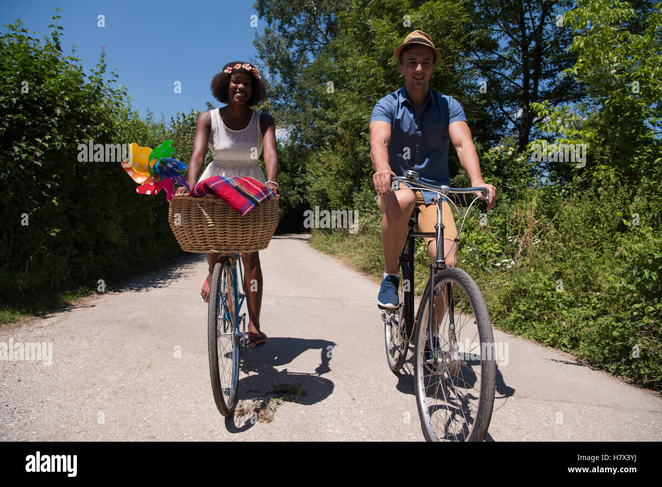 a young man and a beautiful black girl enjoying a bike ride in nature ...