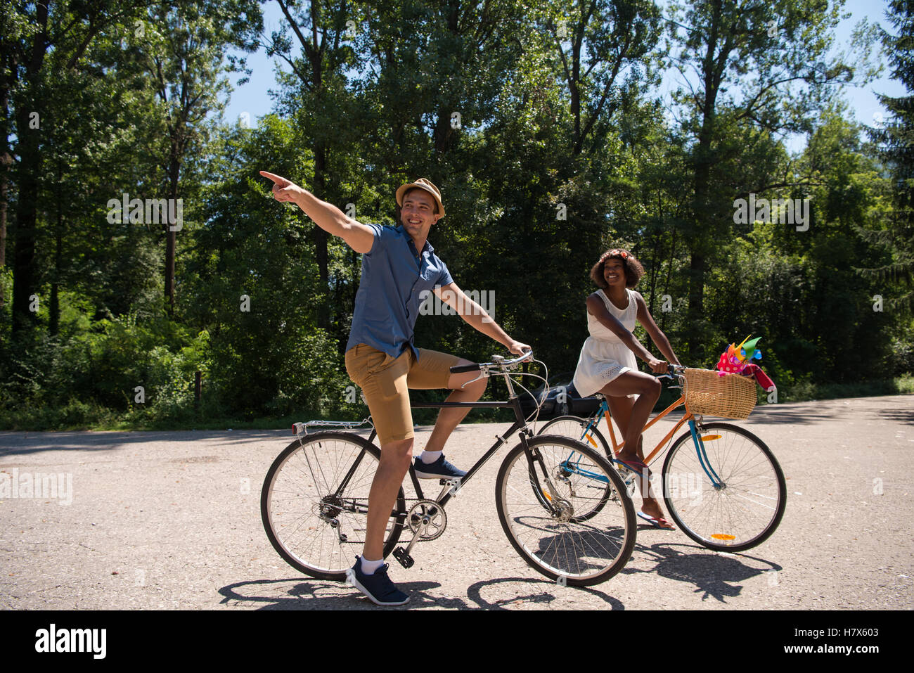 a young man and a beautiful black girl enjoying a bike ride in nature ...