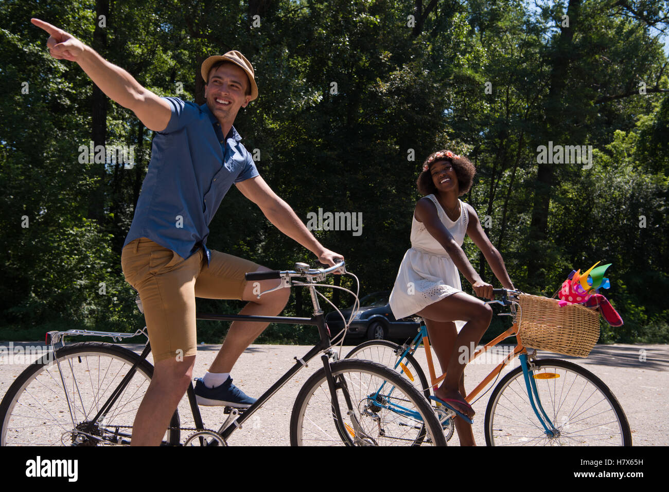 a young man and a beautiful black girl enjoying a bike ride in nature ...