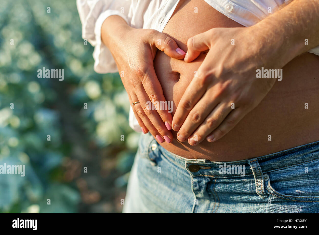 Pregnant woman.Hands embracing pregnant woman's belly outdoors under ...