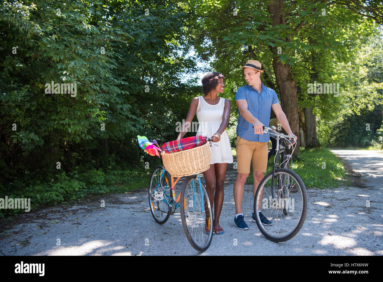 a young man and a beautiful black girl enjoying a bike ride in nature ...