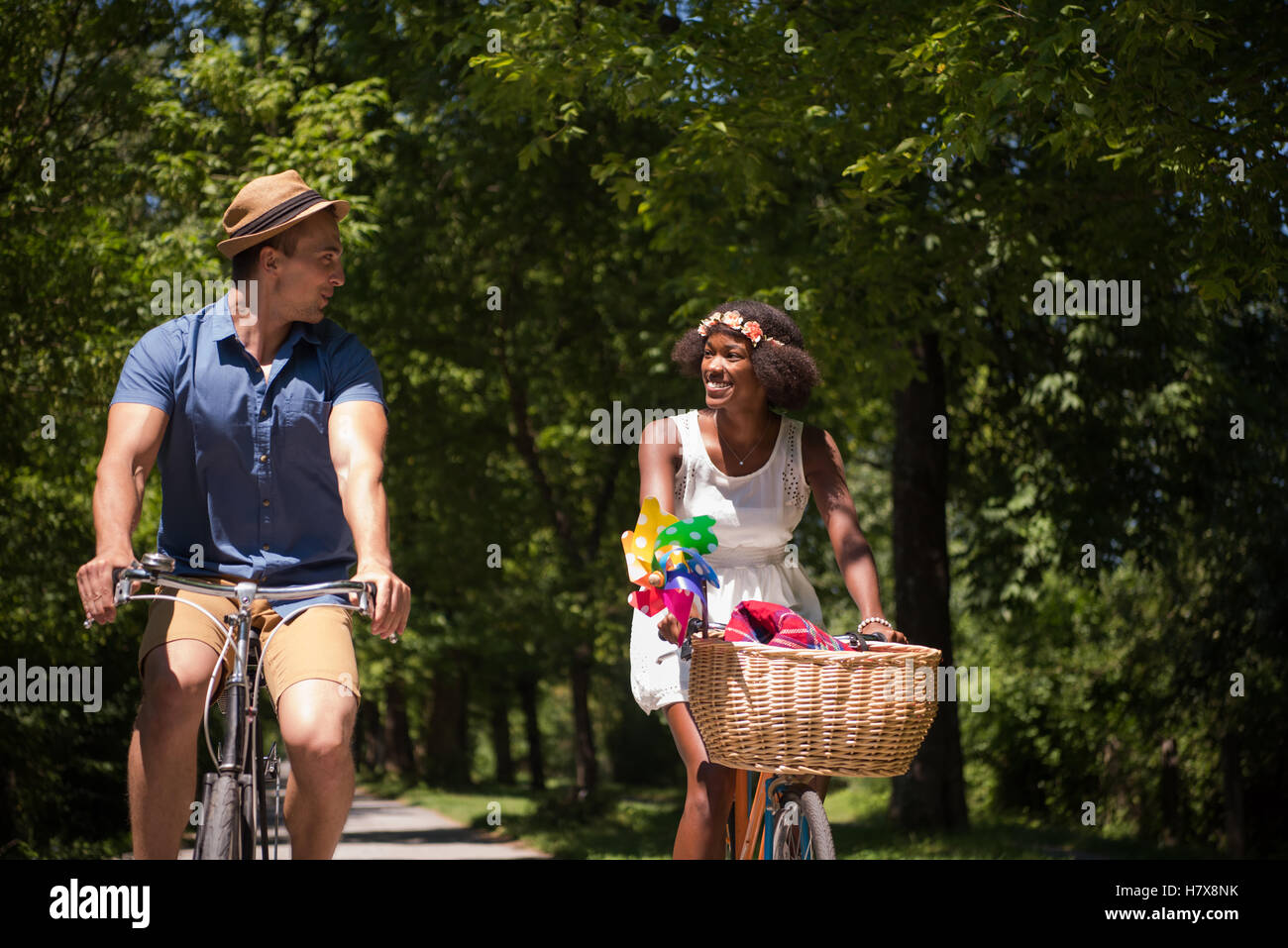 a young man and a beautiful black girl enjoying a bike ride in nature ...