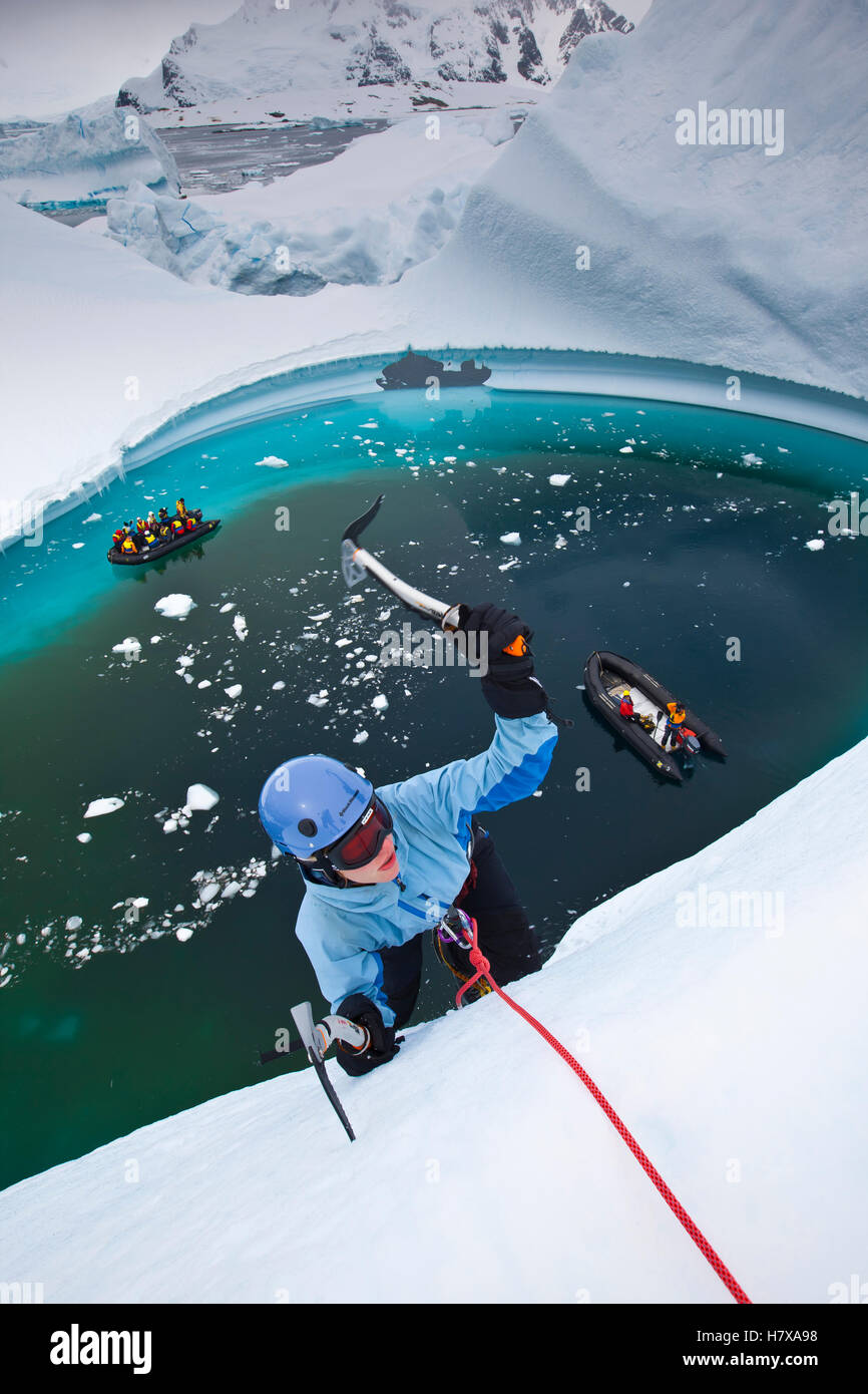 Woman climber ice climbing on grounded iceberg with cruise ship ...