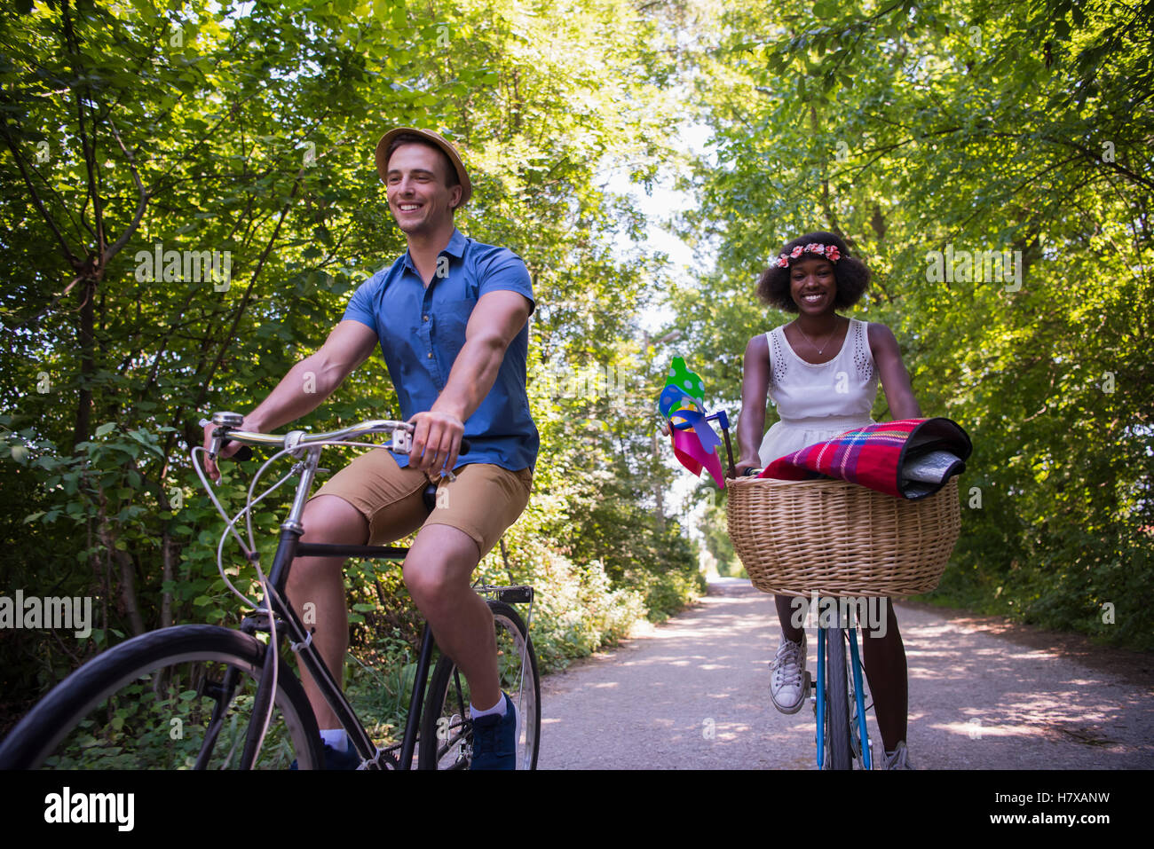 a young man and a beautiful black girl enjoying a bike ride in nature ...