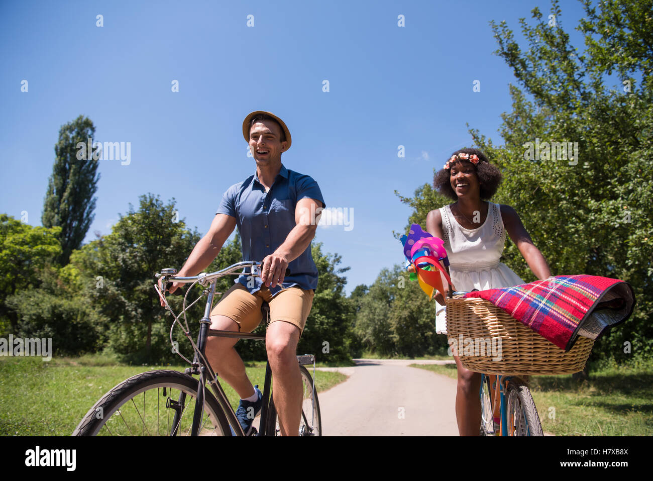 a young man and a beautiful black girl enjoying a bike ride in nature ...