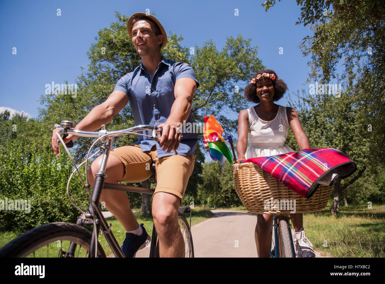 a young man and a beautiful black girl enjoying a bike ride in nature ...
