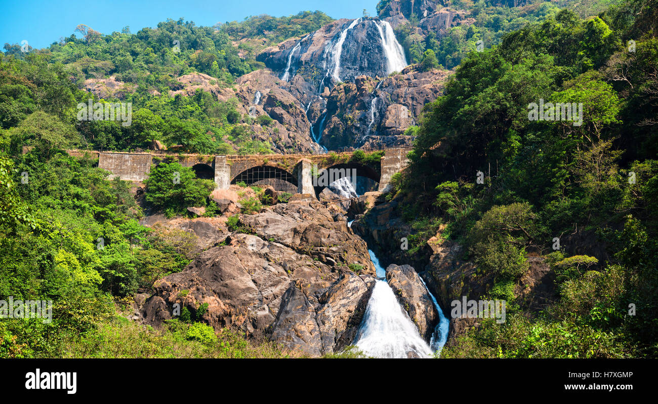 View of the railway bridge in the mountains through the waterfall ...