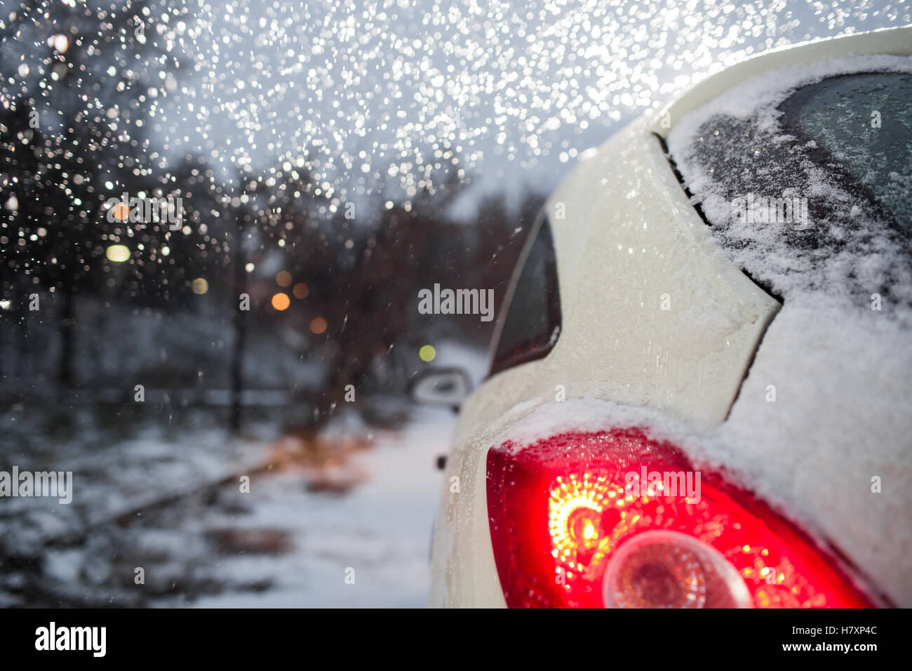 car covered under white first snow. Red taillight, reverse lights and ...