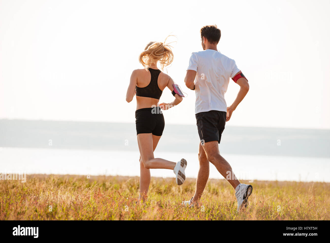 Back view of young fitness man and woman doing jogging sport outdoors ...