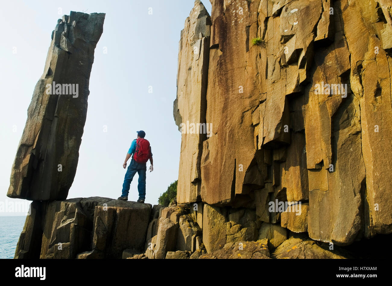 Hiker viewing the Balancing Rock and basalt rock cliffs, Long Island ...