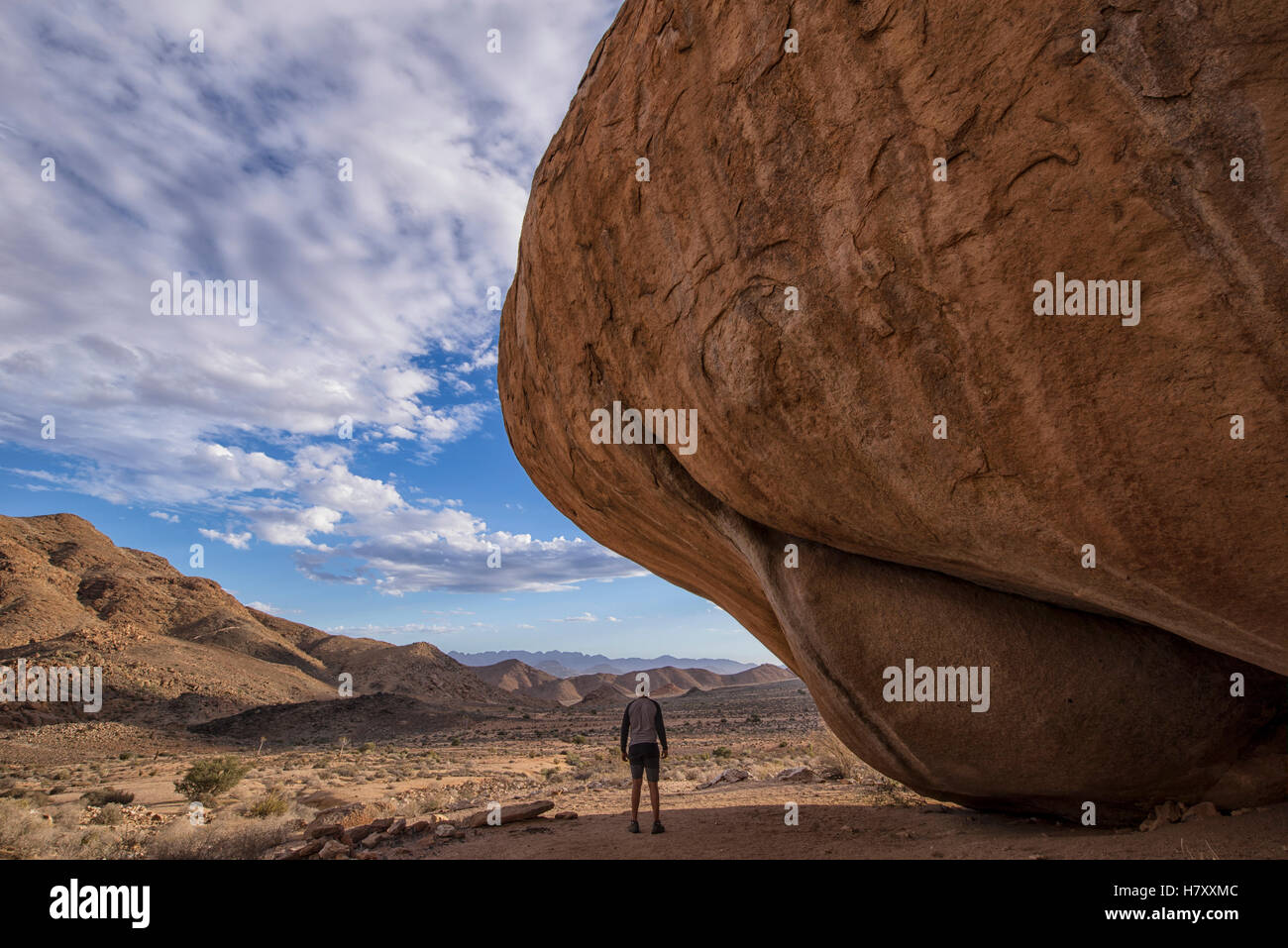 Man standing under a huge boulder in Richtersveld National Park; South ...