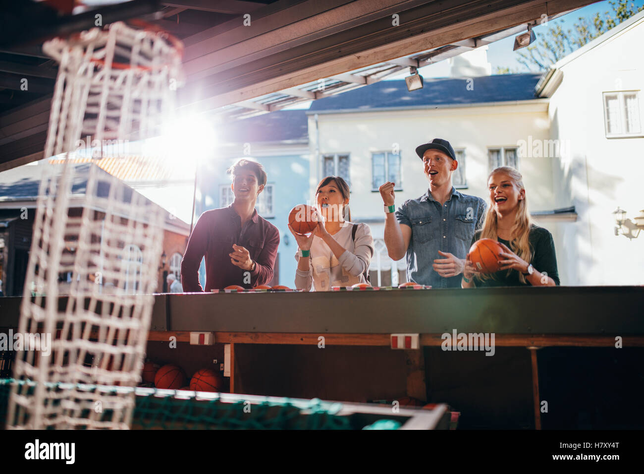 Young people shooting hoops at amusement park. Group of friends playing ...