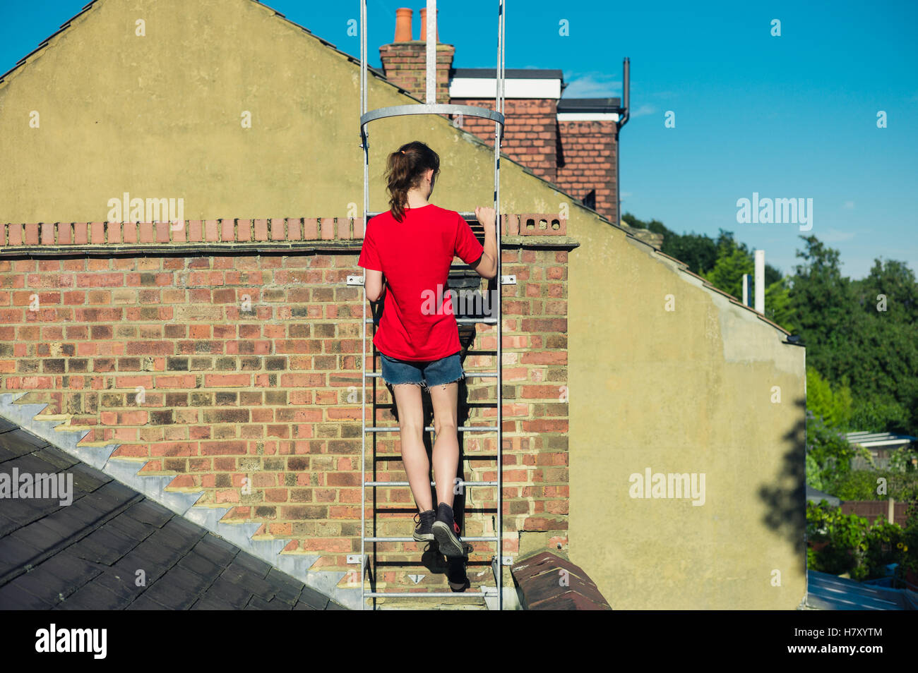 A young woman is climbing a ladder on a roof Stock Photo - Alamy