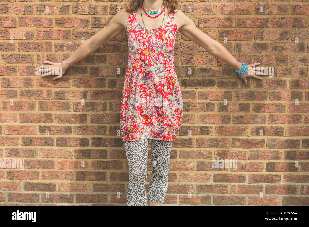 A stylish young woman wearing a colorful dress and bracelets is ...
