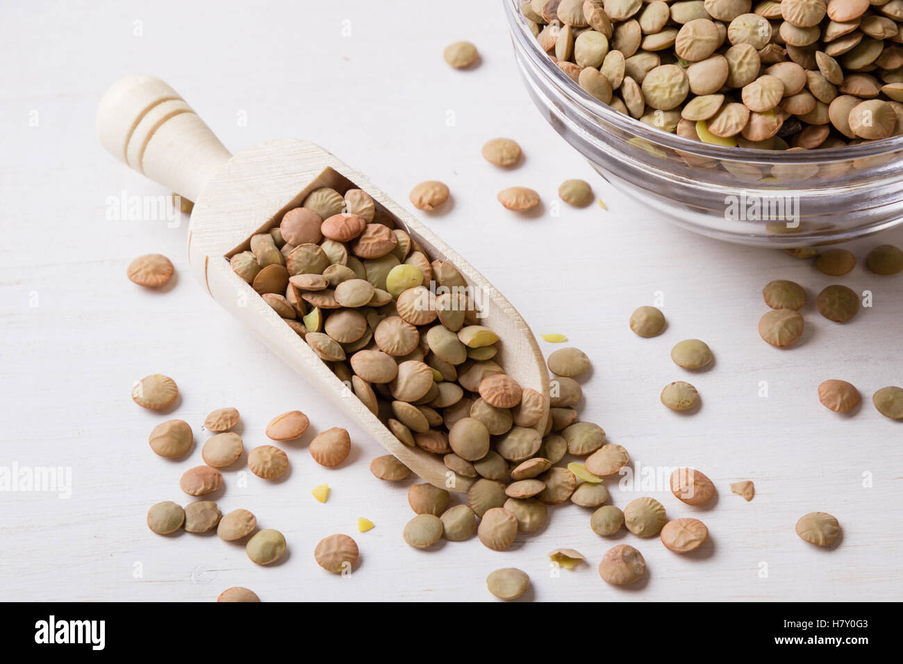 natural organic dry lentils on white table with scoop and glass bowl ...