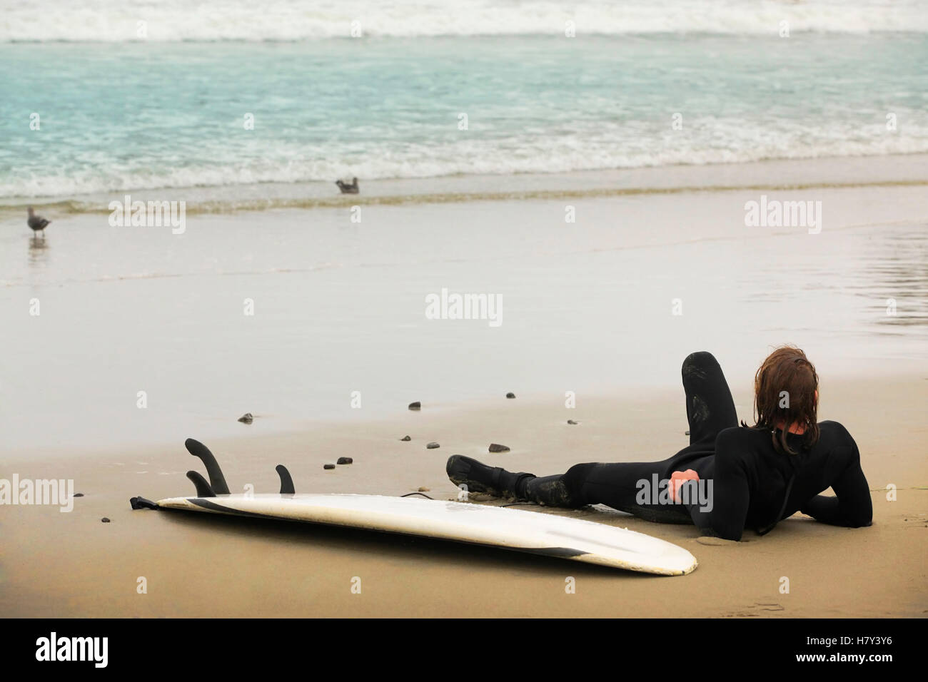 Surfer lying on a board resting on the beach Stock Photo - Alamy