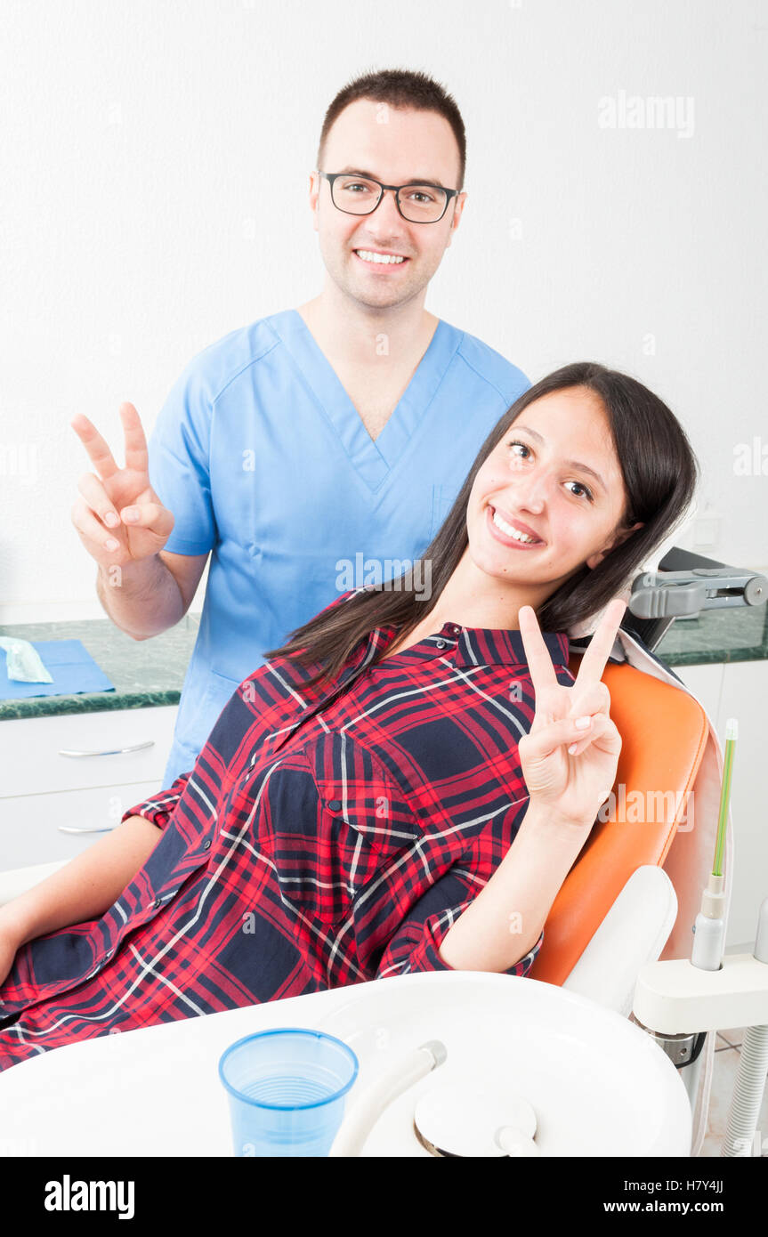 Dentist and patient showing peace gesture and smiling like being ...