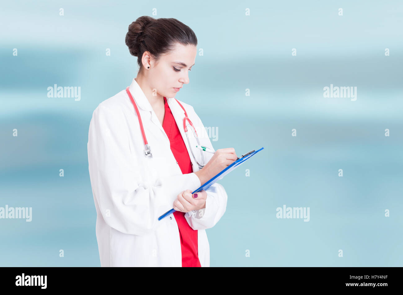 Professional woman medic writing something on clipboard as prescription ...