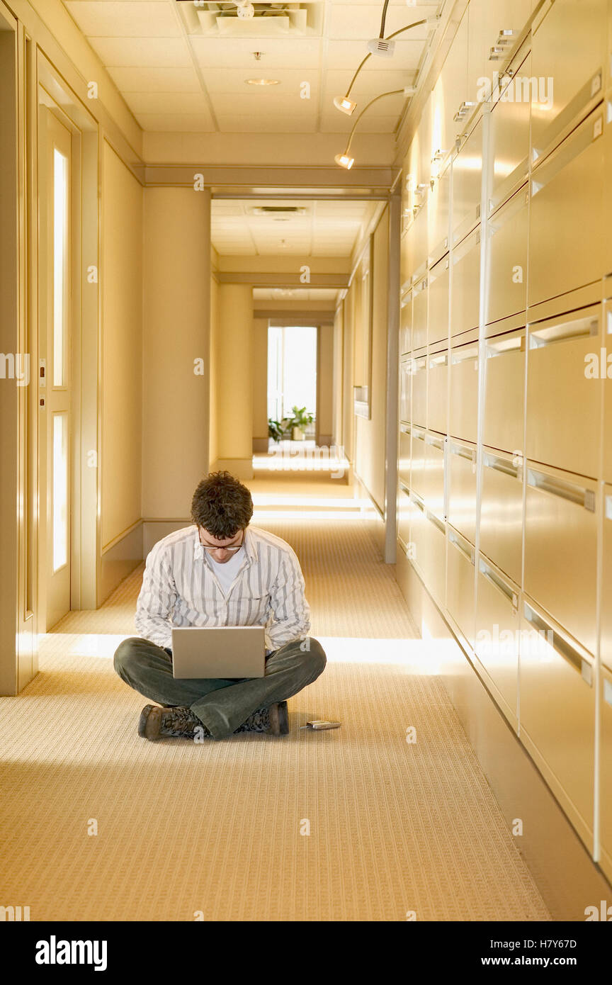 man sitting in hallway working on laptop computer Stock Photo - Alamy