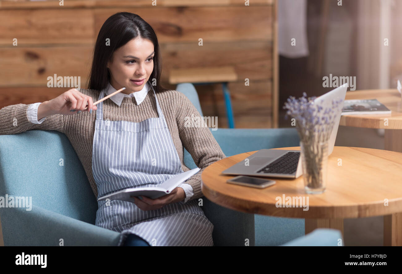 Concentrated young woman making notes and using laptop Stock Photo - Alamy