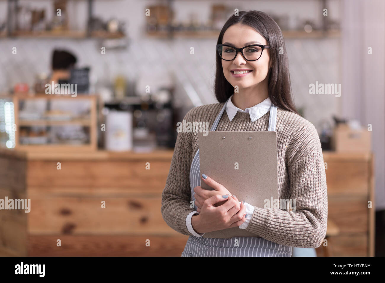 Pretty bespectacled woman smiling and holding folder Stock Photo - Alamy