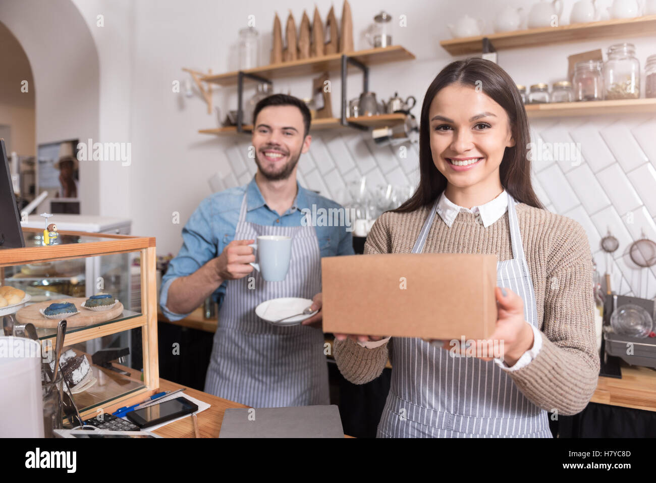 Charming smiling waiters holding cup and box Stock Photo - Alamy