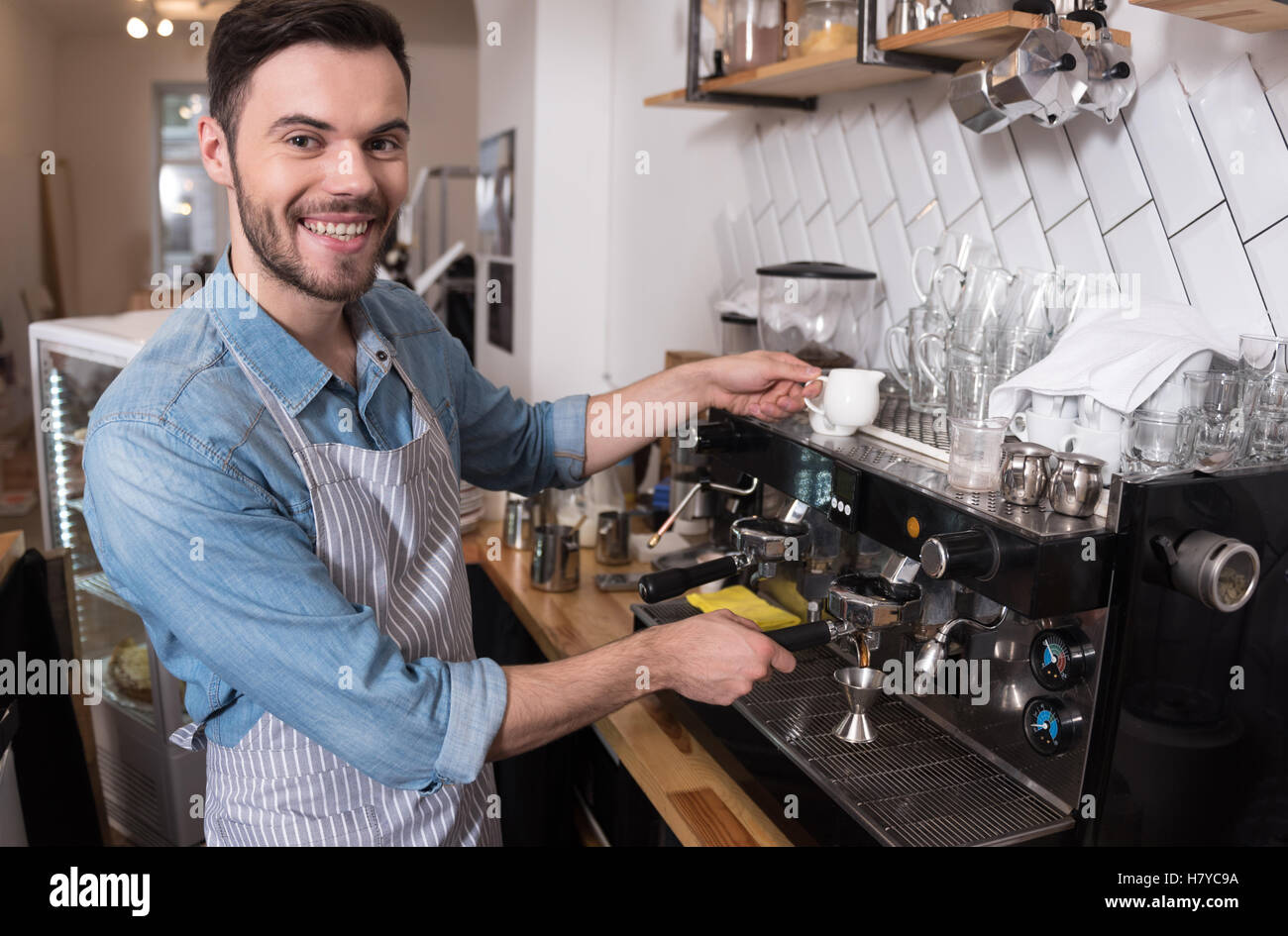 Joyful handsome waiter using coffee machine Stock Photo - Alamy
