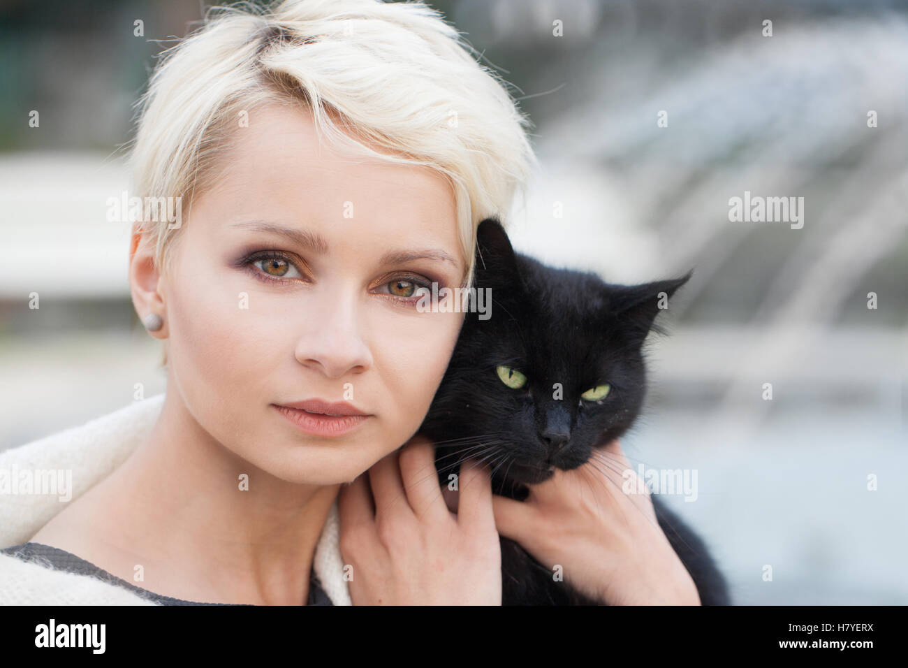 a beautiful blonde woman with a black cat, holding a black cat ...