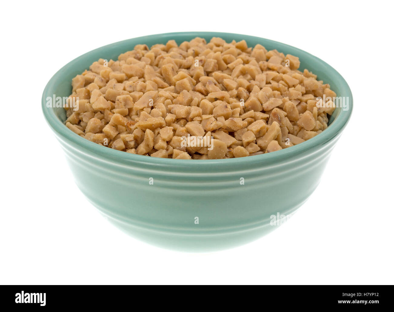 A green bowl filled with toffee bits isolated on a white background ...