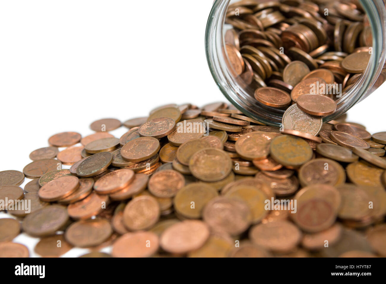Coins spilling out of glass jar on white background Stock Photo - Alamy