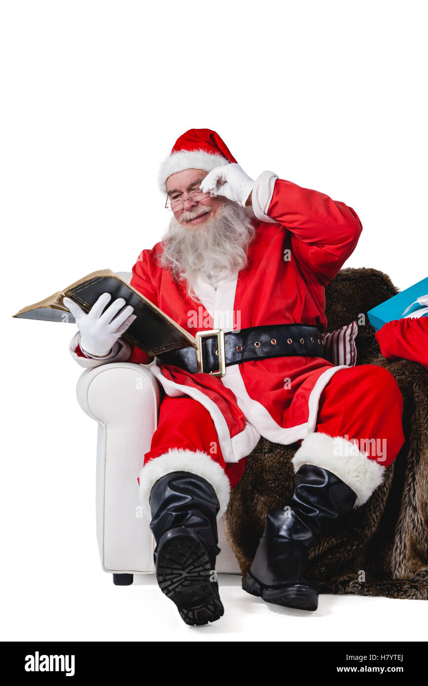 Santa reading bible with sack of christmas present beside him Stock ...