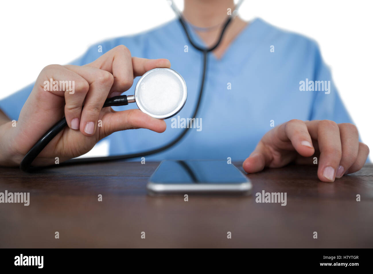 Mid-section of female doctor examining mobile phone with a stethoscope ...