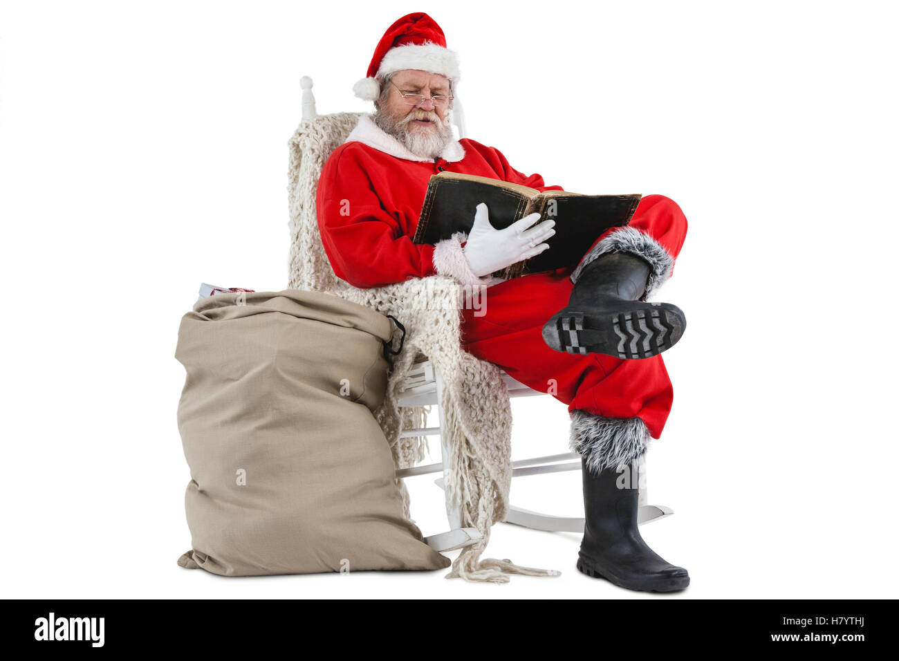 Santa claus reading bible with sack of christmas present beside him ...
