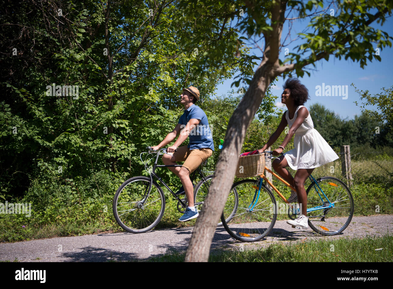 a young man and a beautiful black girl enjoying a bike ride in nature ...