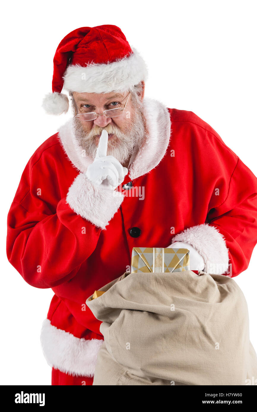 Santa claus with finger on lips and holding a gifts Stock Photo - Alamy
