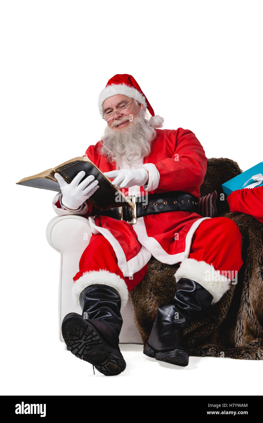 Santa reading bible with sack of christmas present beside him Stock ...