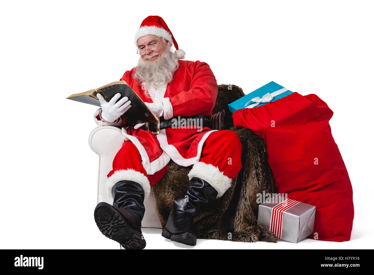 Santa reading bible with sack of christmas present beside him Stock ...