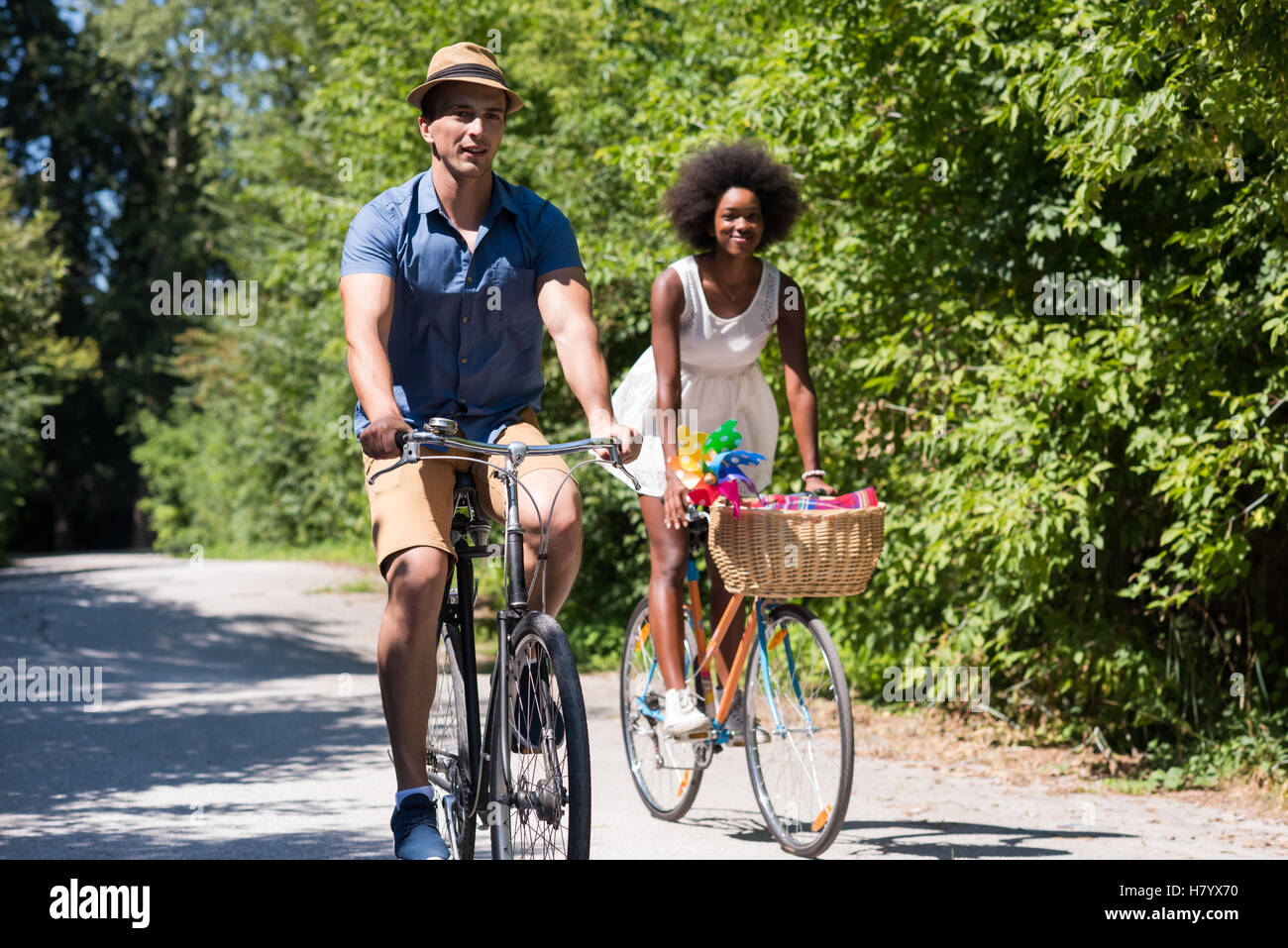 a young man and a beautiful black girl enjoying a bike ride in nature ...