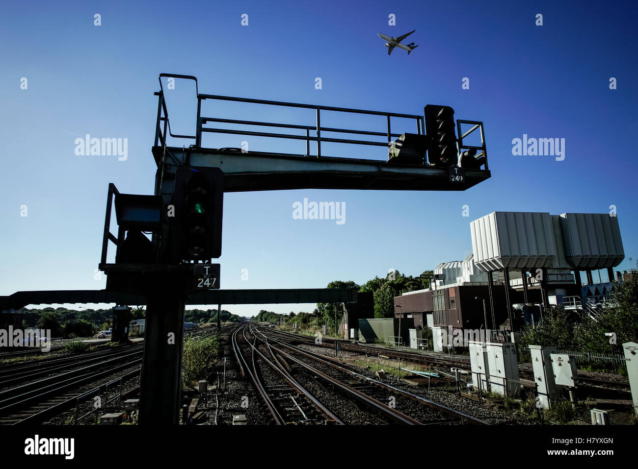 A plane flies overhead at Gatwick train station Stock Photo - Alamy