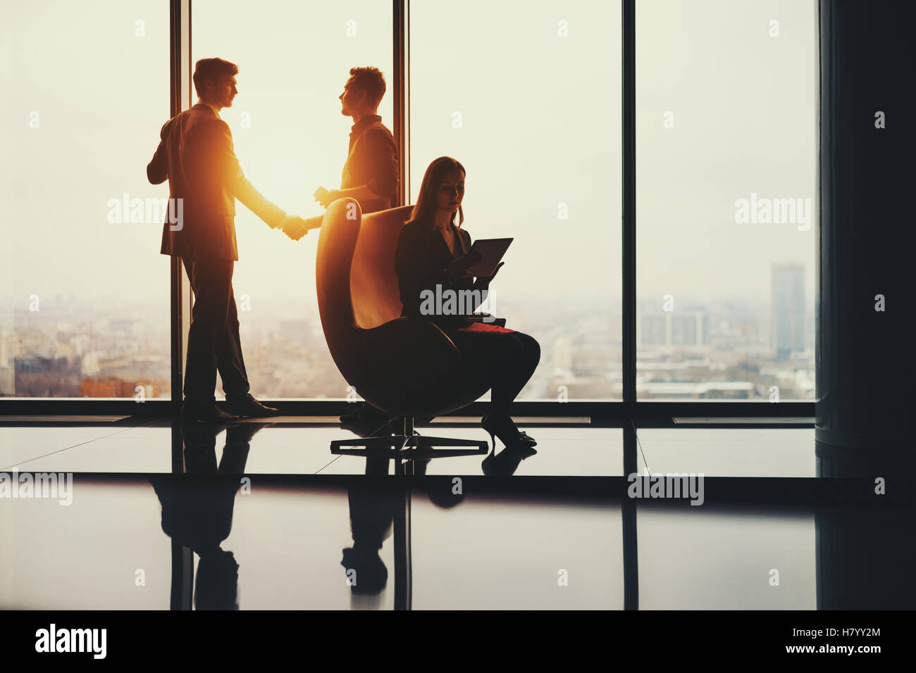 Two young businessmen in office interior finishing their deal with ...