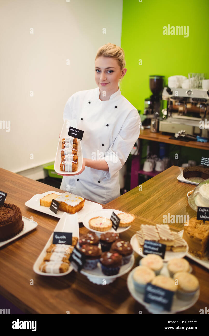 Portrait of worker holding sweet food at counter Stock Photo - Alamy