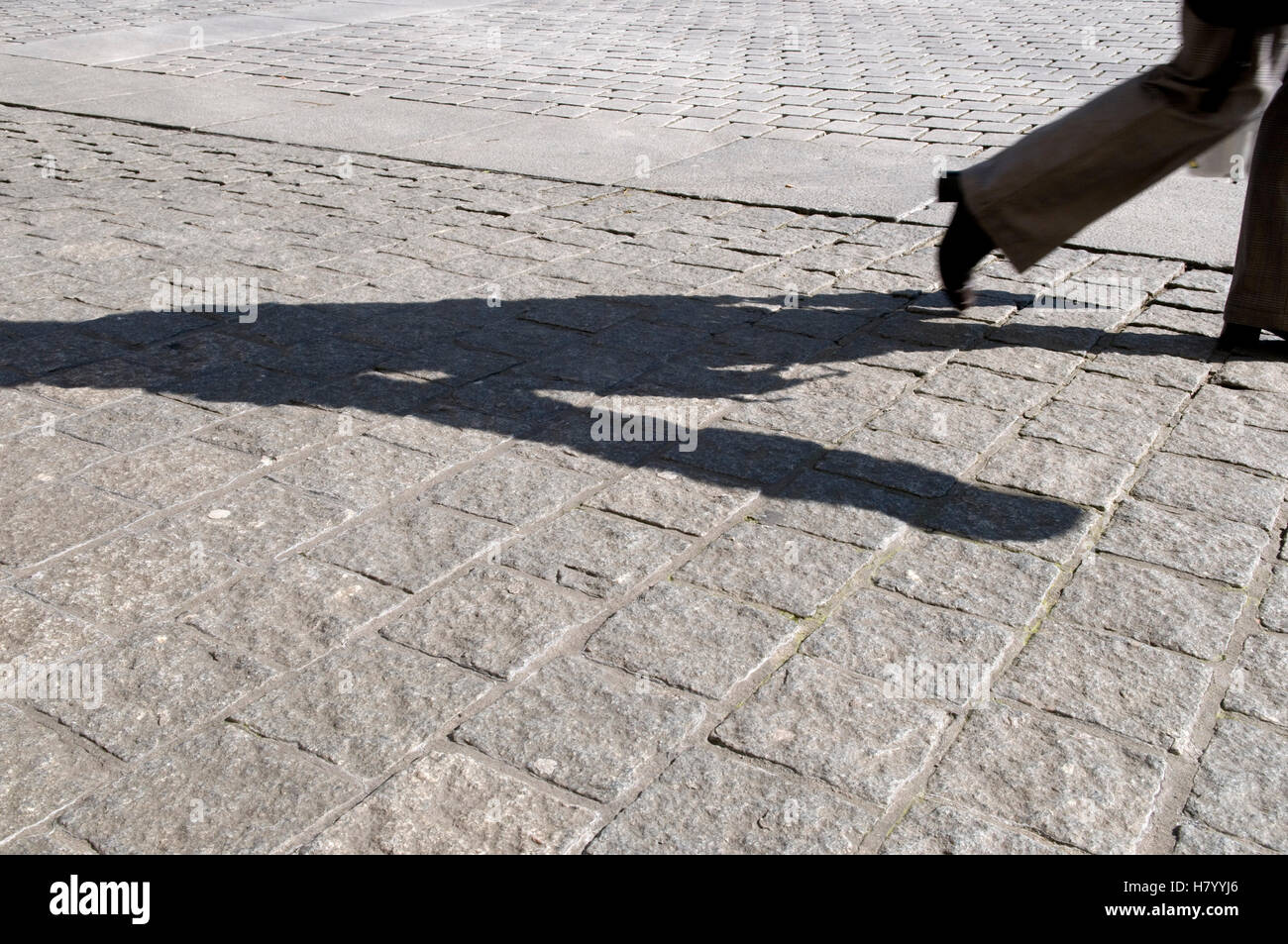 Walker casting shadows on the pavement Stock Photo - Alamy