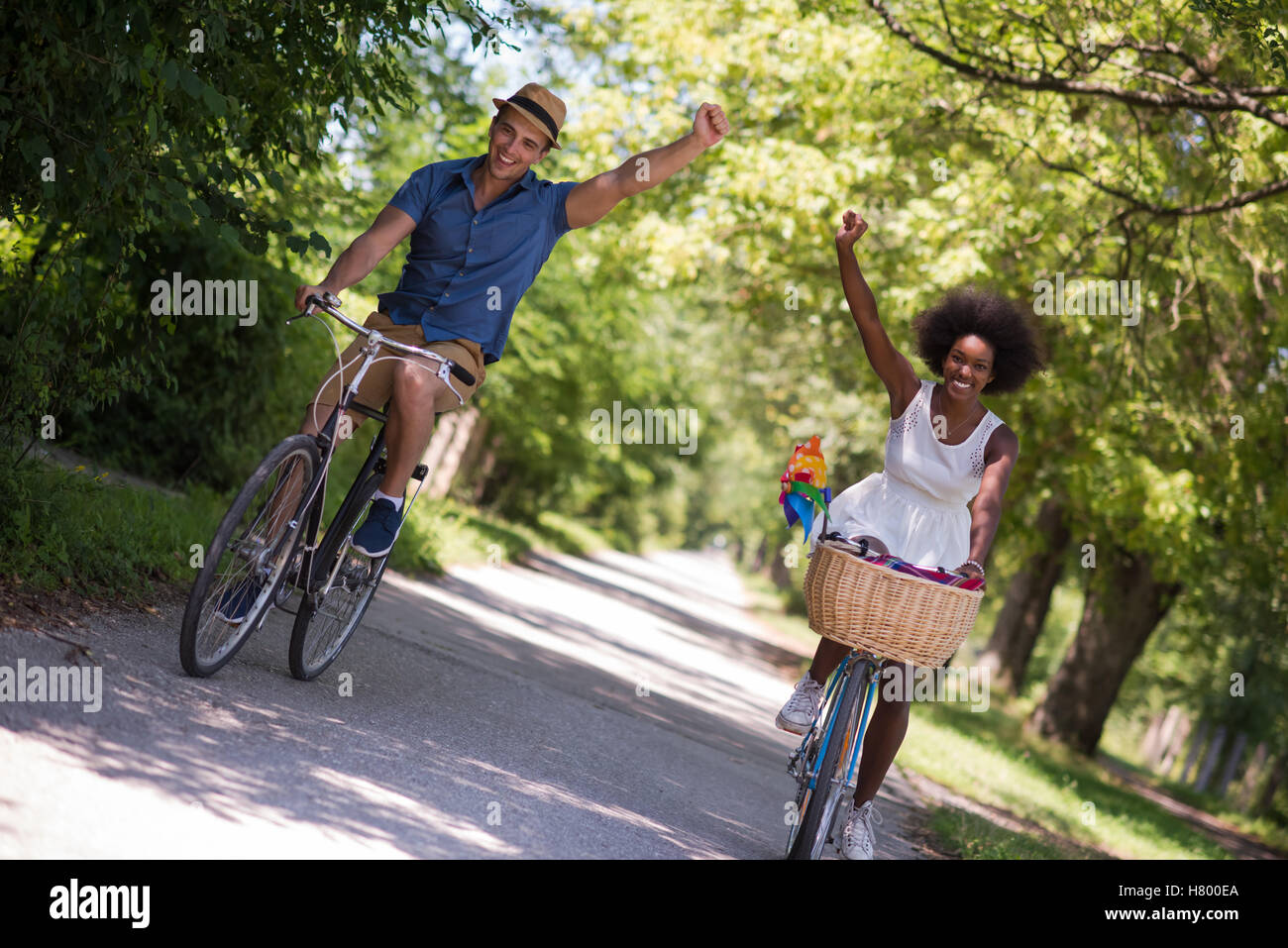 a young man and a beautiful black girl enjoying a bike ride in nature ...