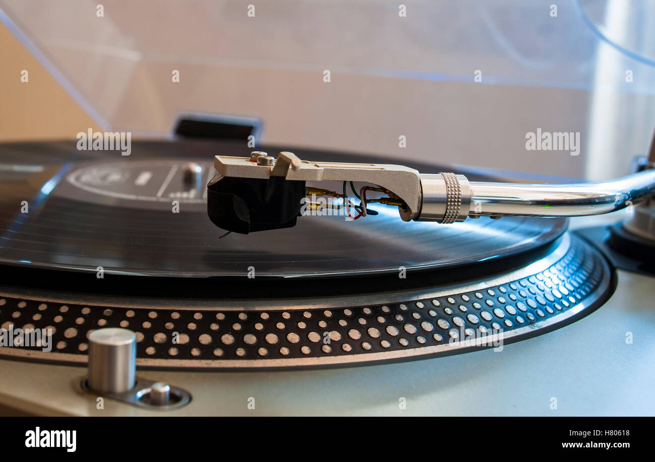 Close up of a turntable needle head playing music from an lp. (shallow ...