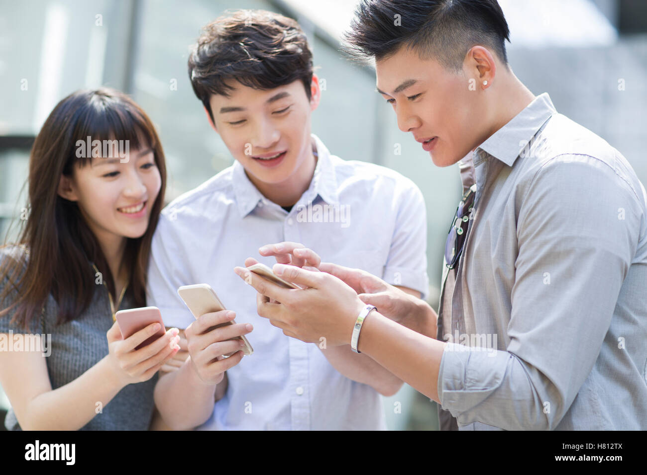 Young Chinese friends looking at smart phones Stock Photo - Alamy