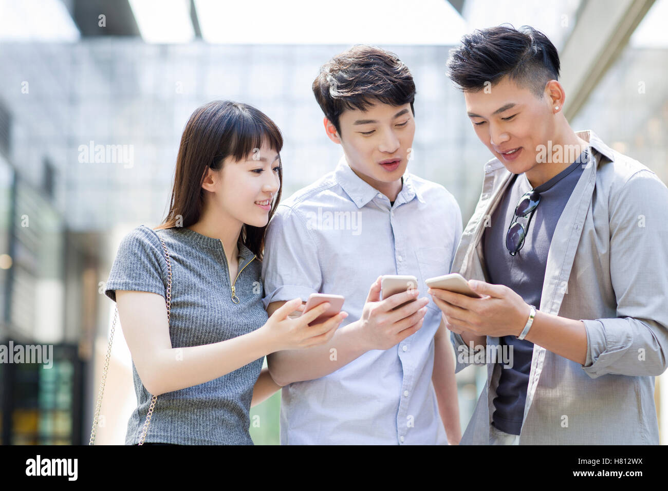 Young Chinese friends looking at smart phones Stock Photo - Alamy
